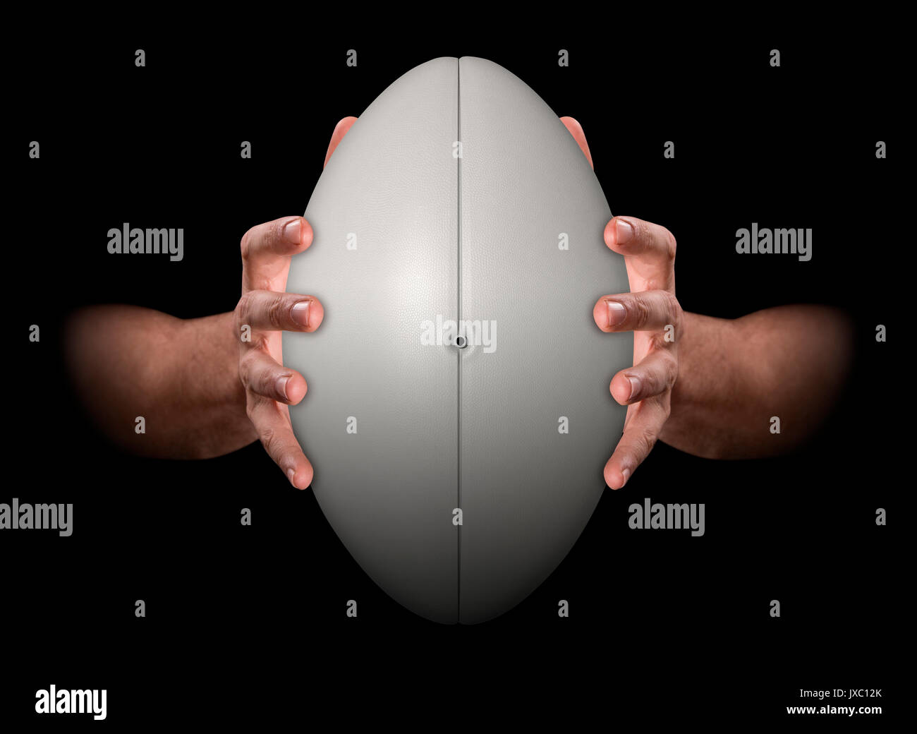 A pair of male hands clamping a rugby ball on an isolated dark ...