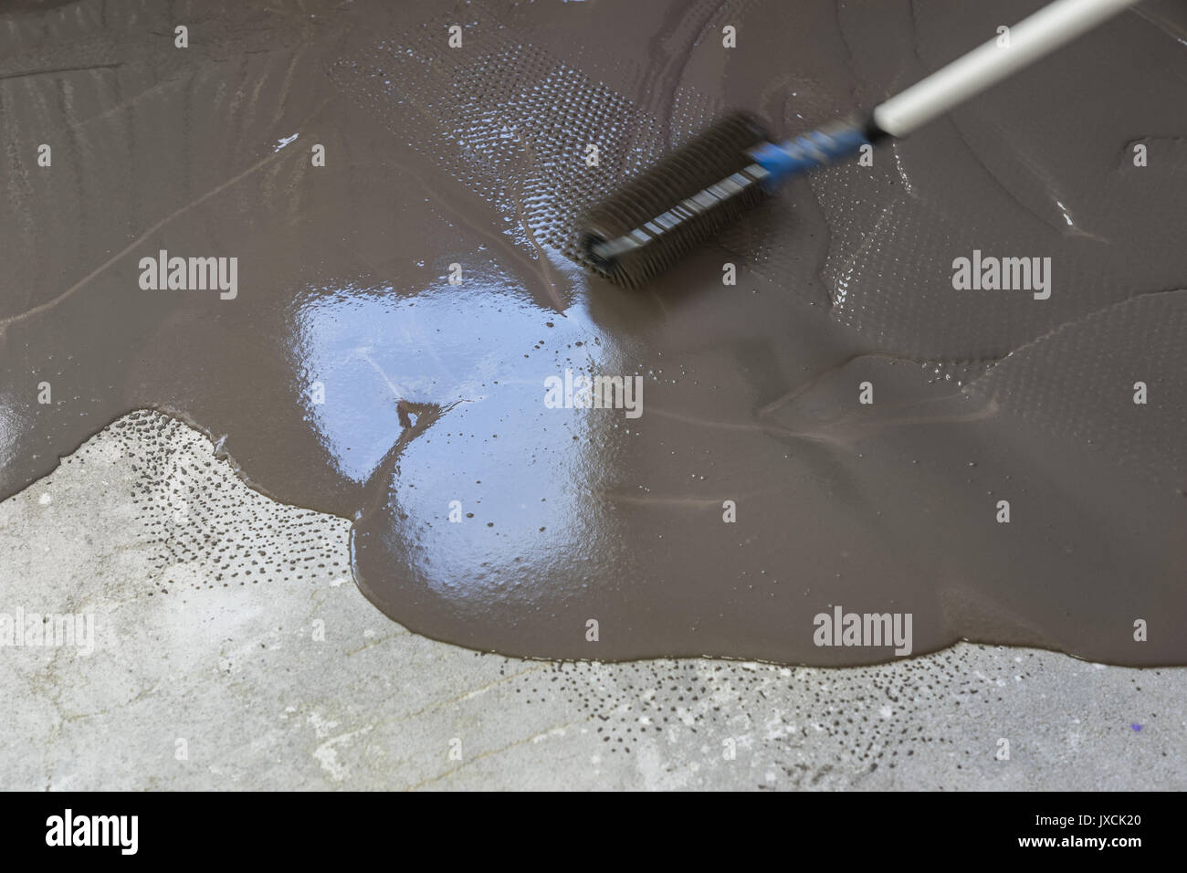 Spreading self leveling plaster with a special roller. Interior of ...