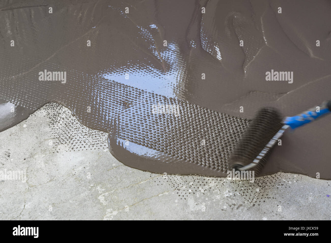 Spreading self leveling plaster with a special roller. Interior of ...