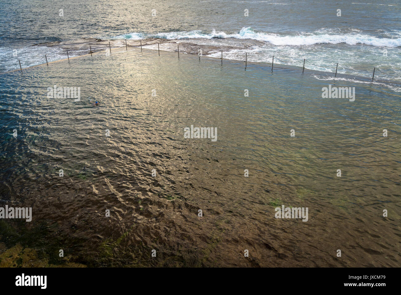 Swimmer swimming in late afternoon, Wylies Baths, a tidal pool near ...
