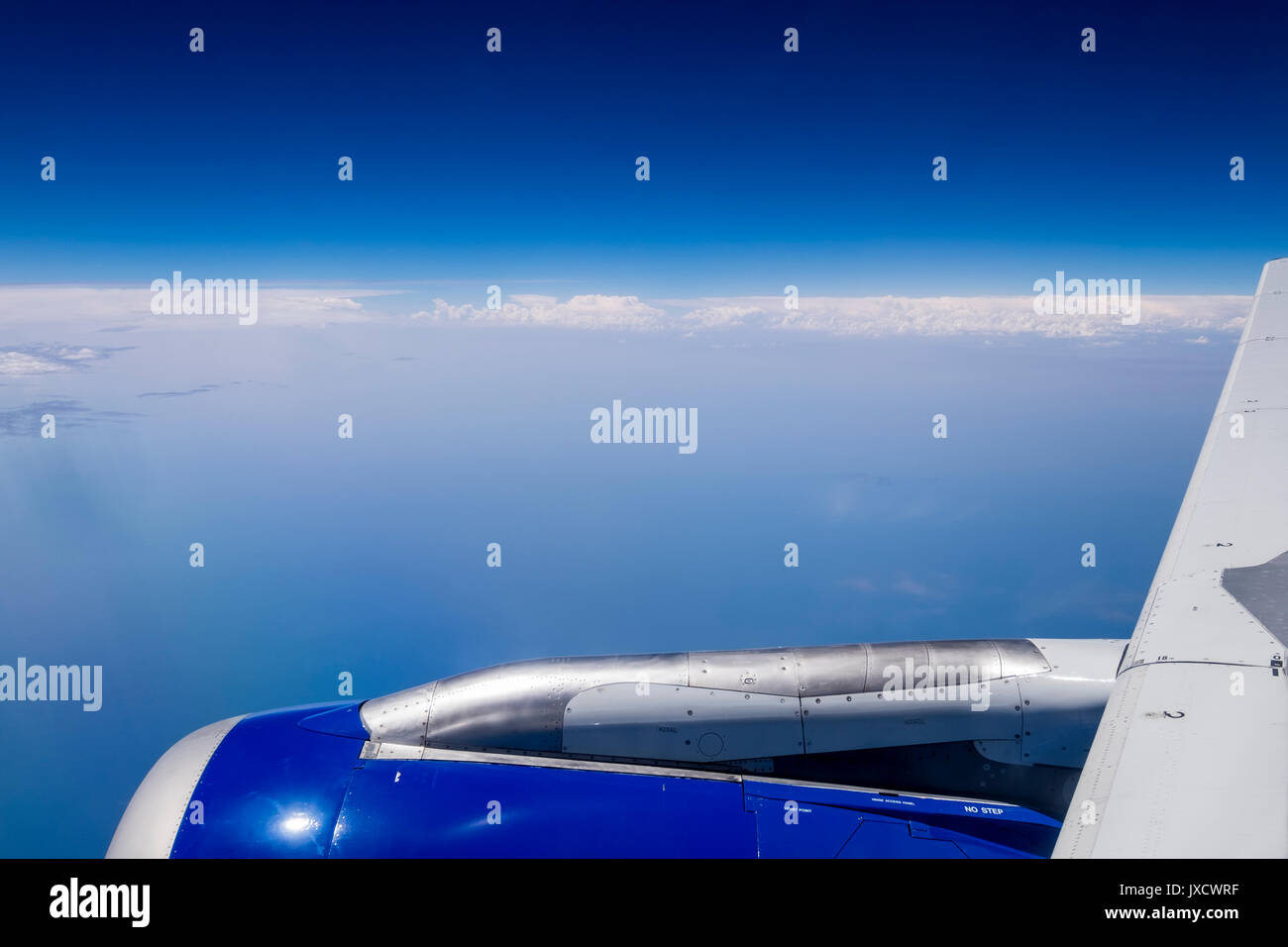 Clouds and blue sky seen from an airplane looking out over the jet ...