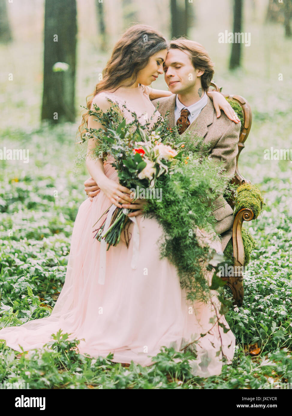 The beautiful bride is holding the huge colourful bouquet and sitting ...