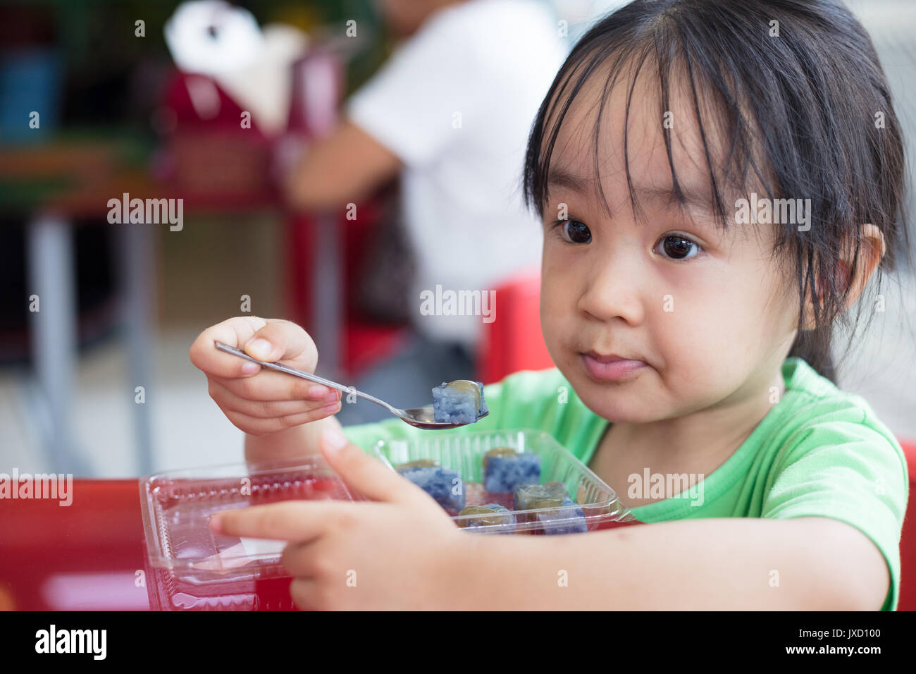 Asian little Chinese girl eating glutinous rice in outdoor restaurant ...