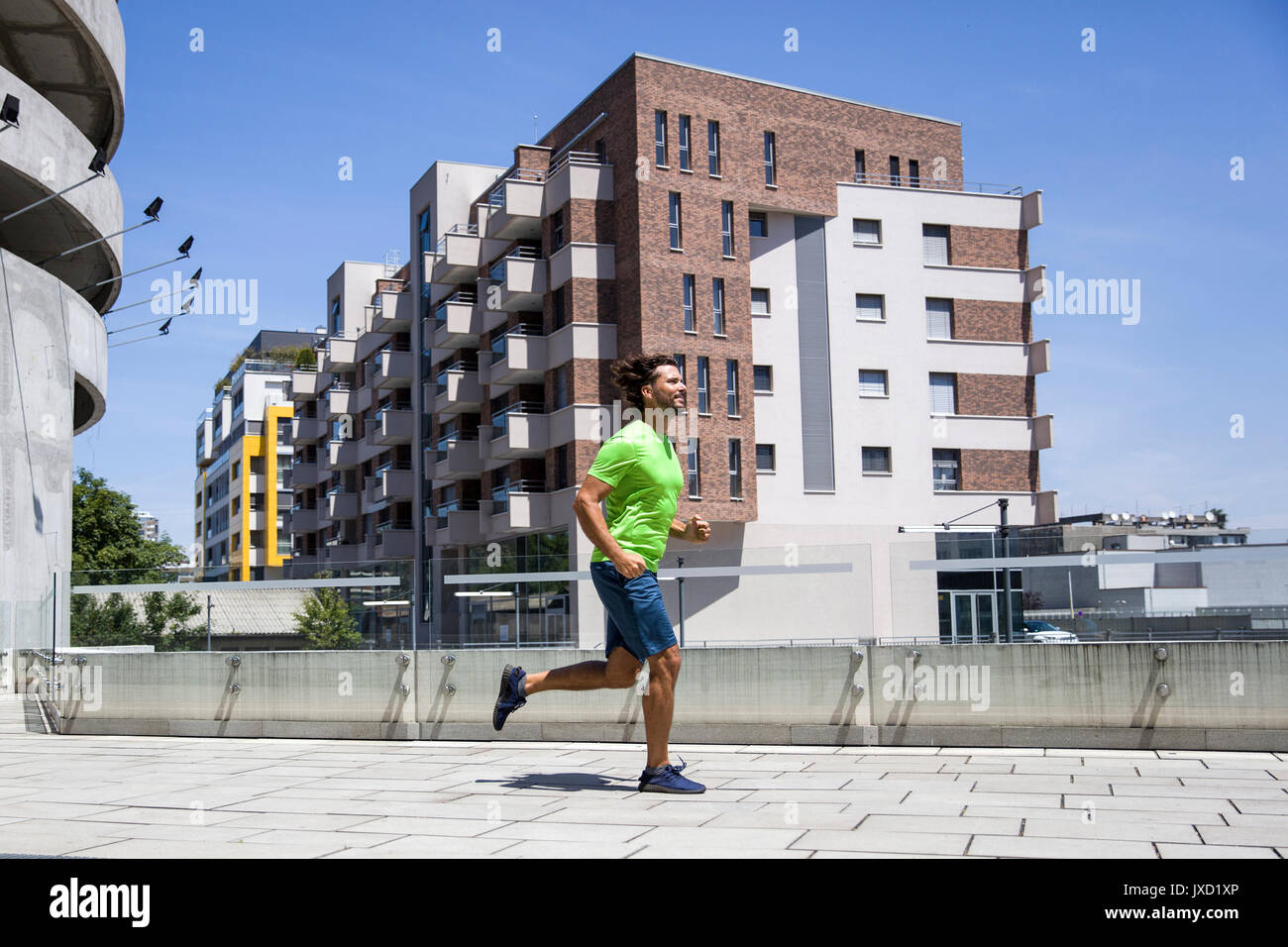 Young man running on the street in urban environment at sunny day Stock ...