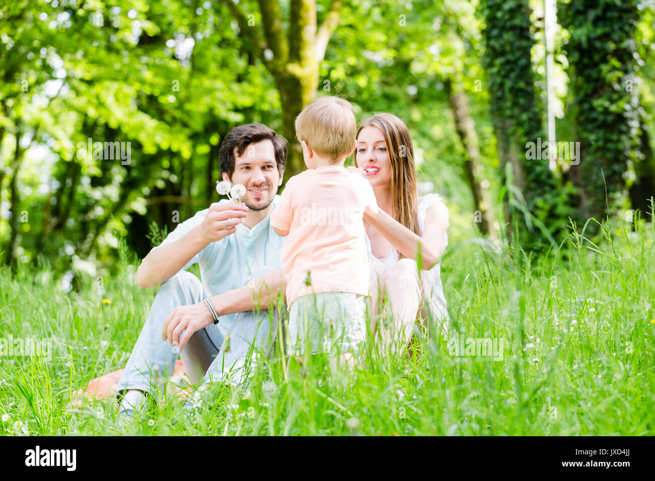 Little boy running over meadow with family in back Stock Photo - Alamy
