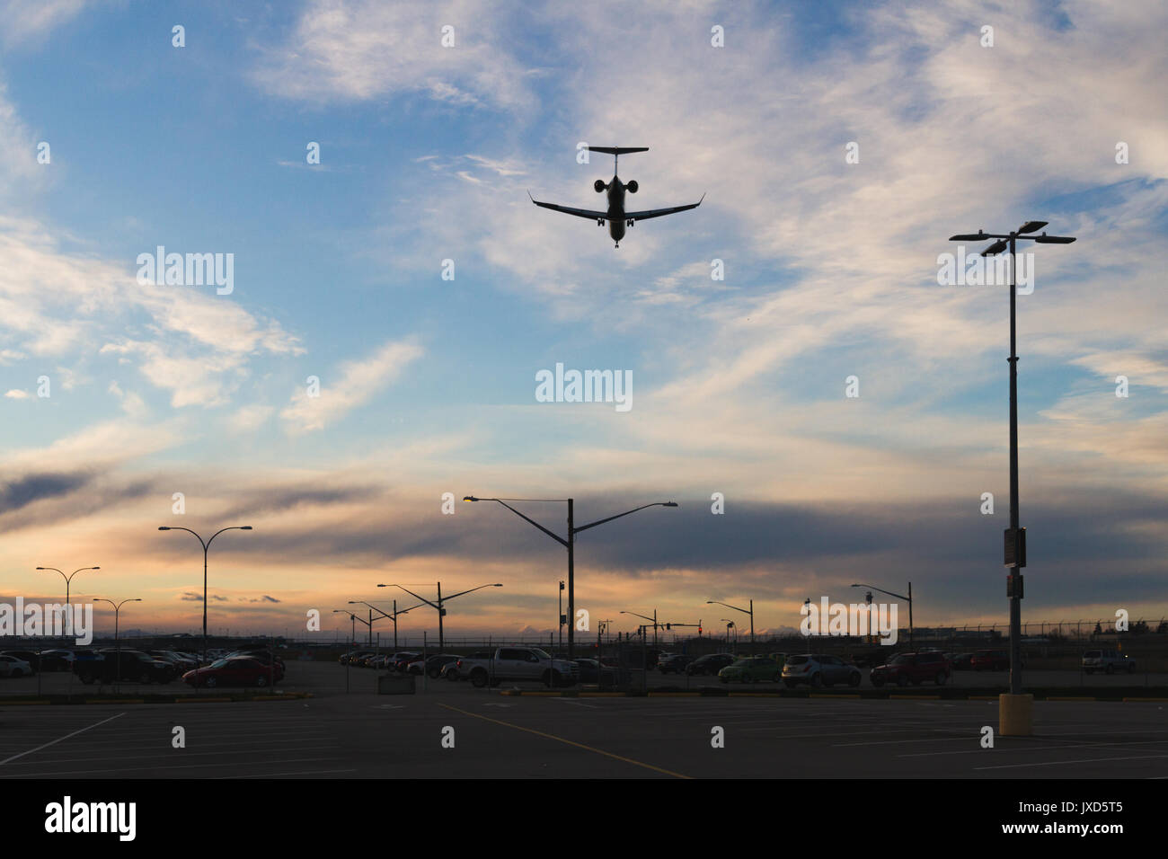 Parking lot full of cars with airplane flying over at sunset Stock ...