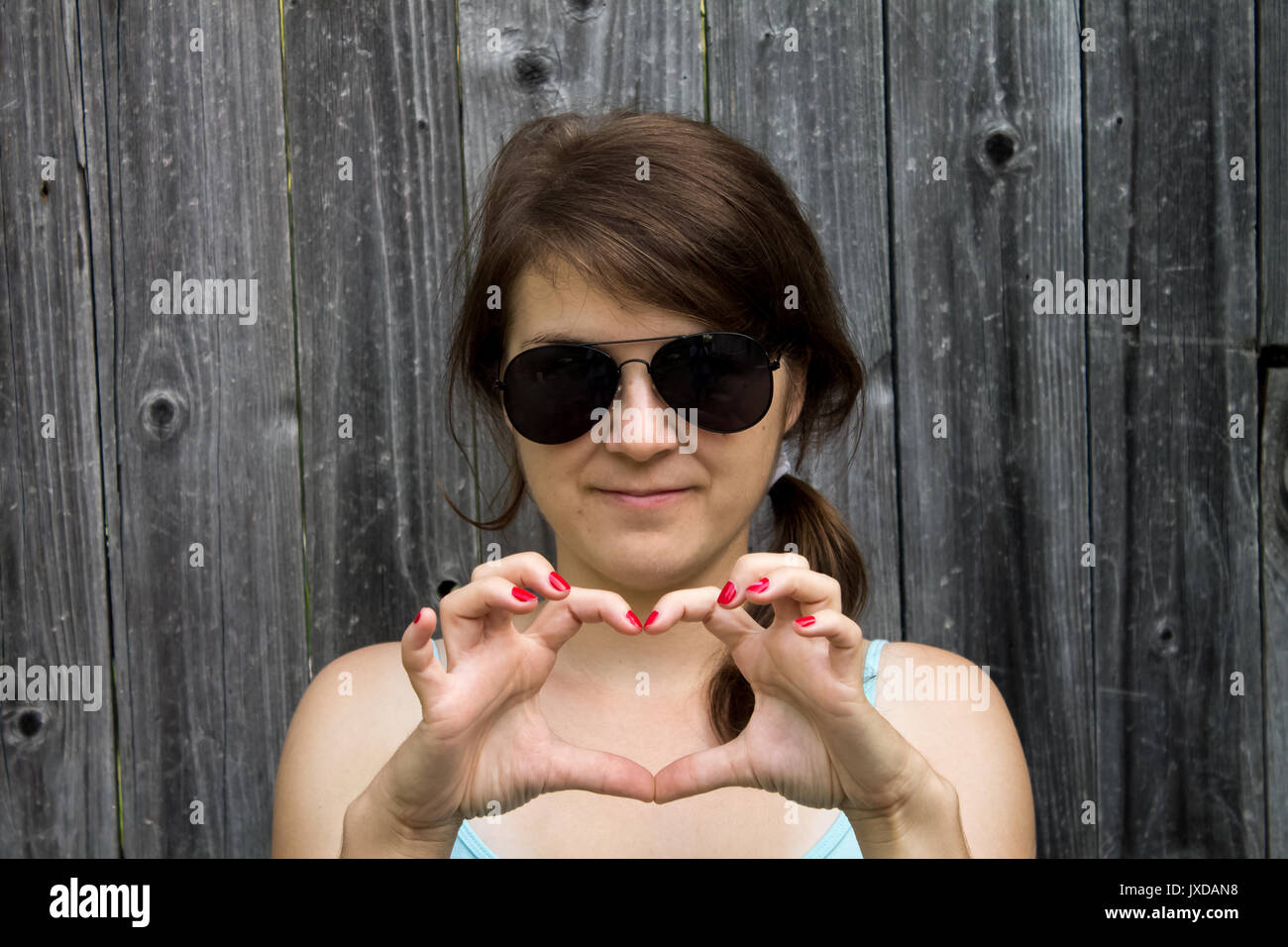 Happy young woman smile with hands form heart shape gesture, with red ...