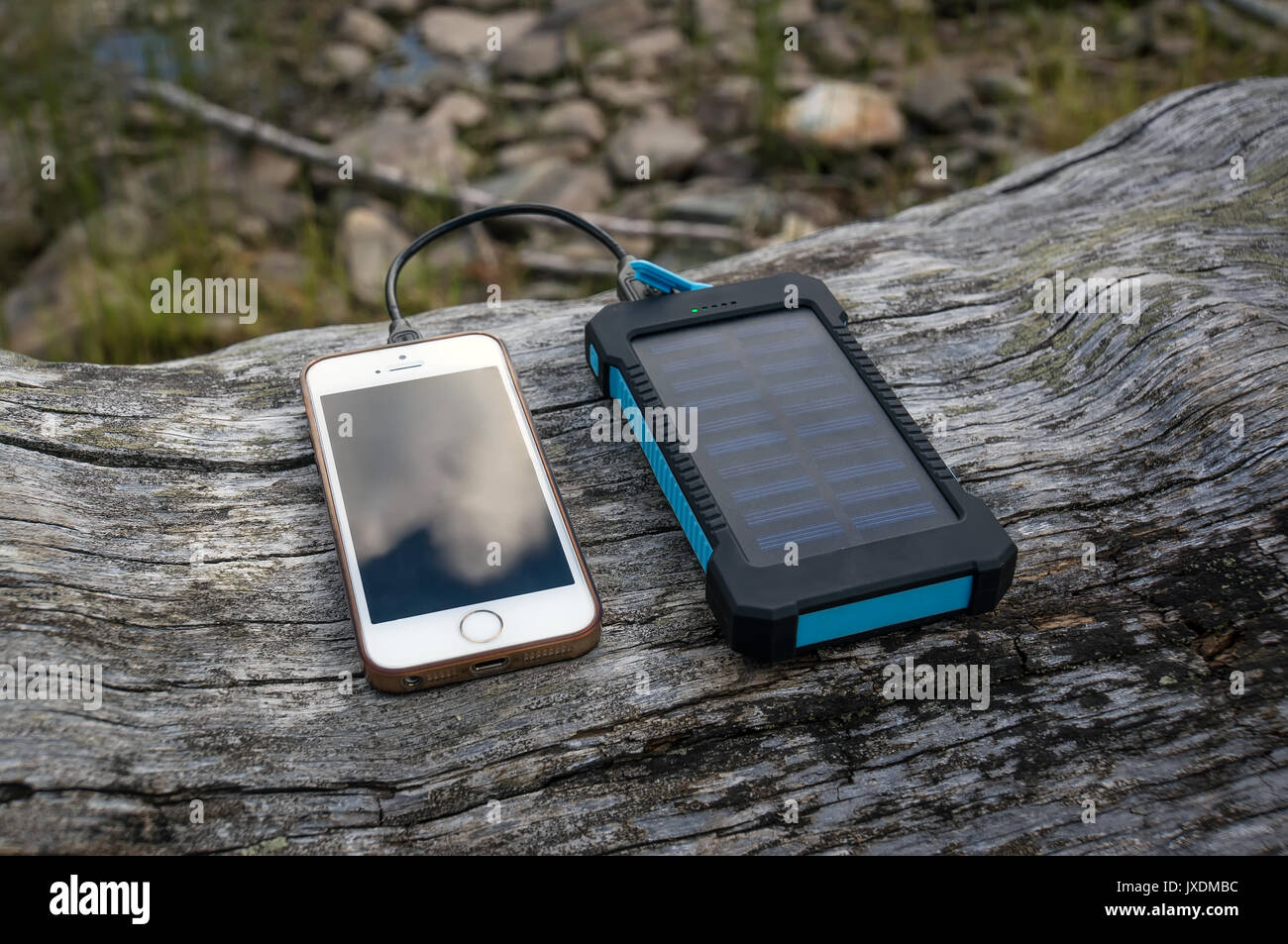 Portable solar panel for charging mobile devices lying on a log in the ...
