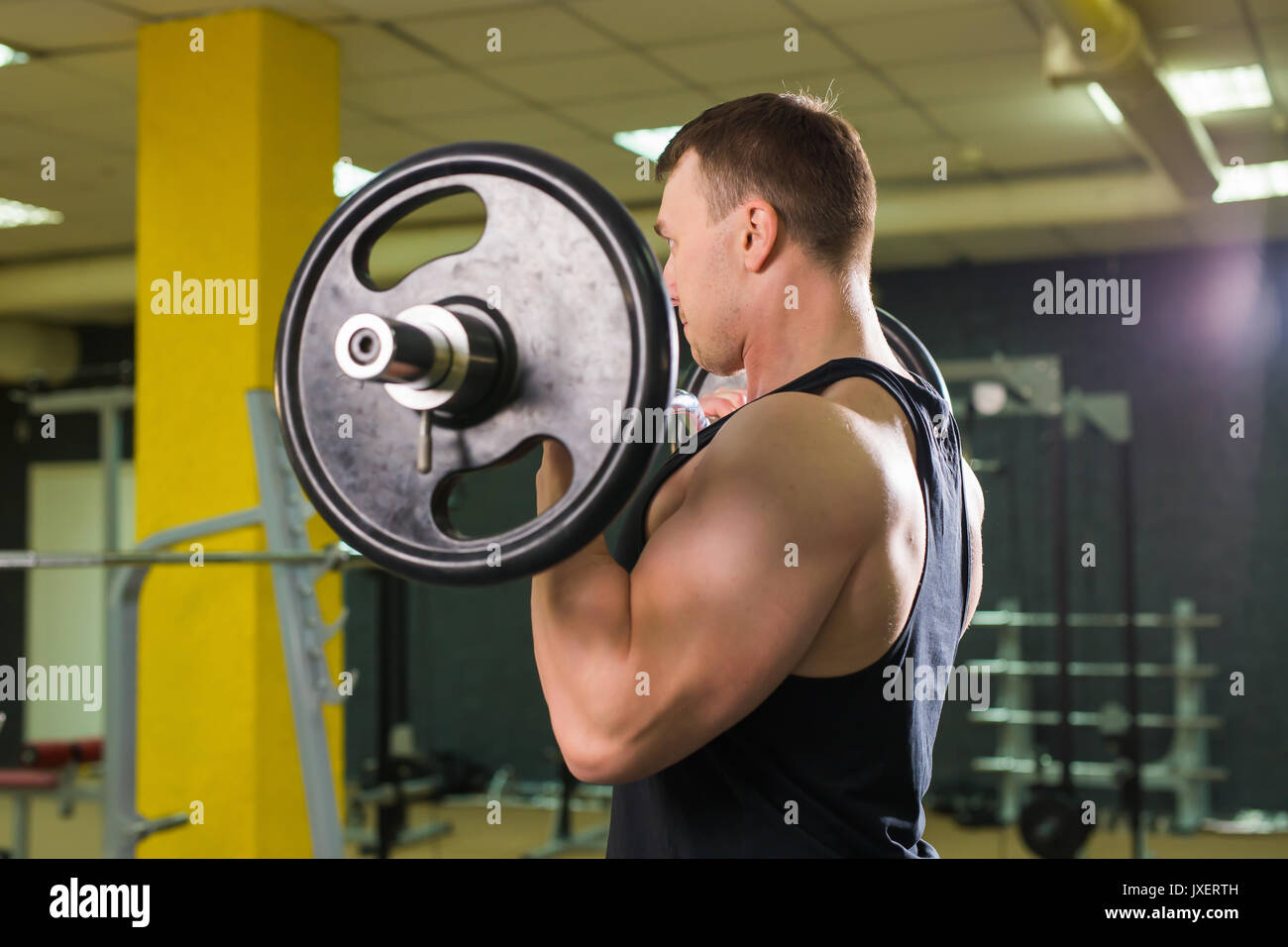 Strong man - bodybuilder with dumbbells in a gym, exercising with a ...