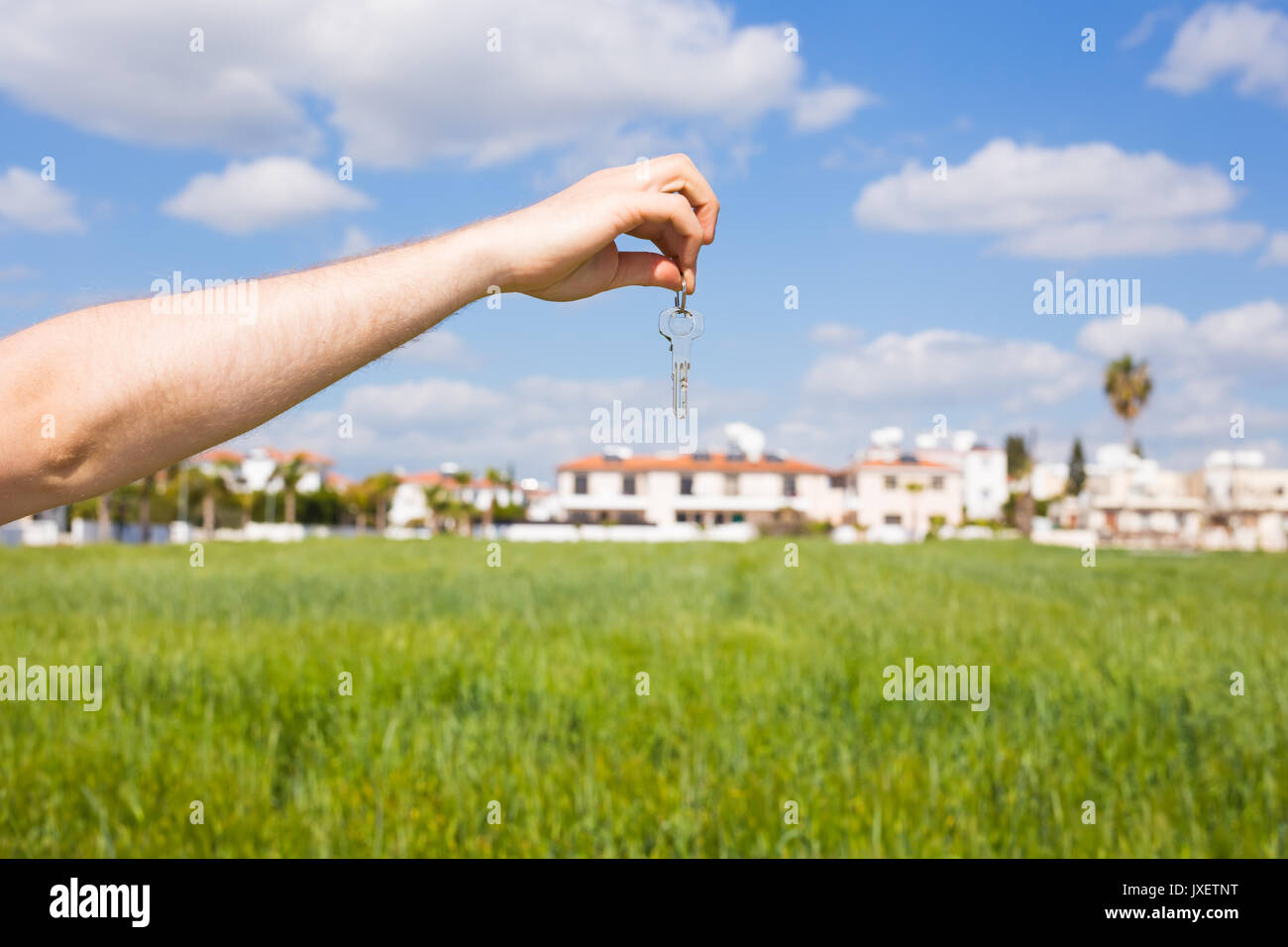 Holding house keys on house shaped keychain close up in front of a new ...