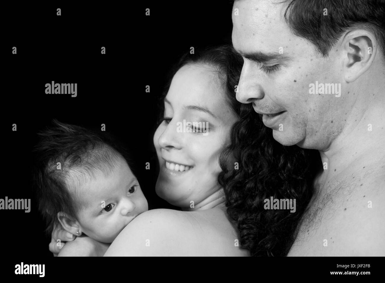 Parents with their one month baby girl on black background Stock Photo ...