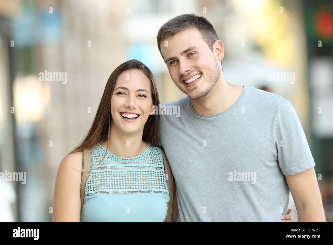 Front view portrait of a happy couple walking together on the street ...