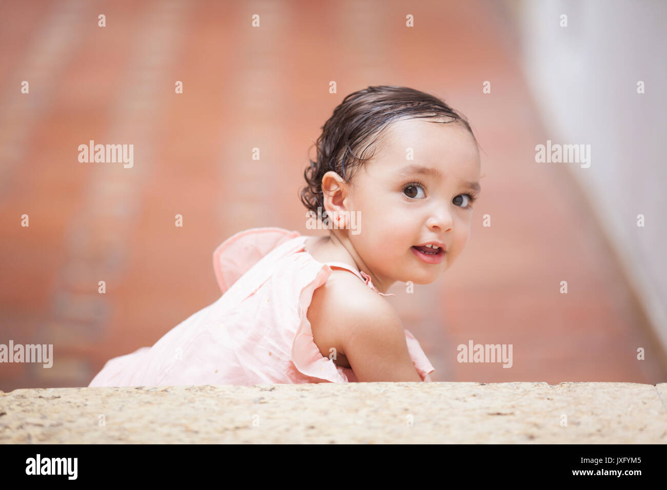 Baby girl looking over her shoulder Stock Photo - Alamy