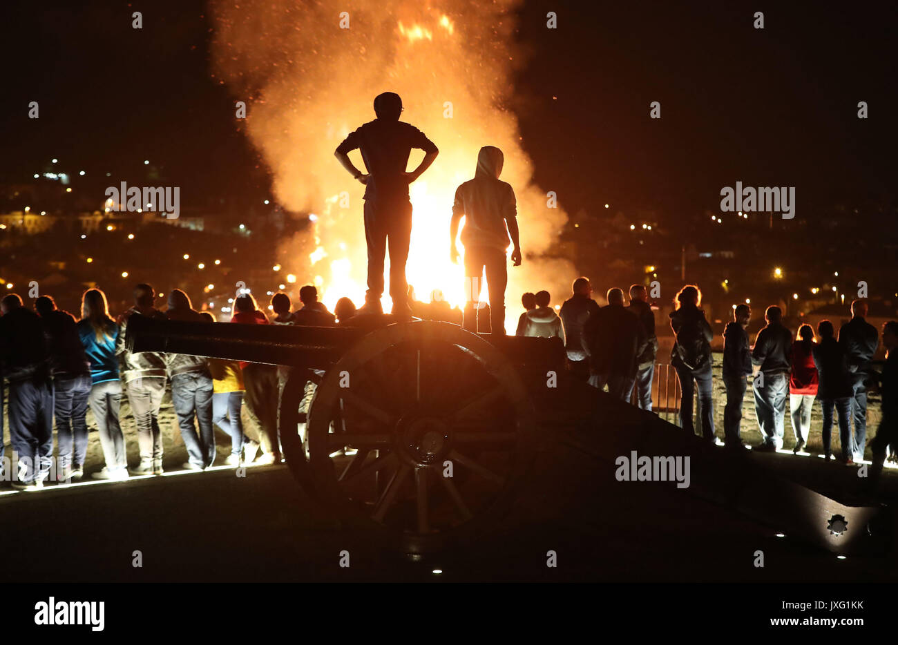 People watch a bonfire, from the top of a cannon on Derry city walls in ...