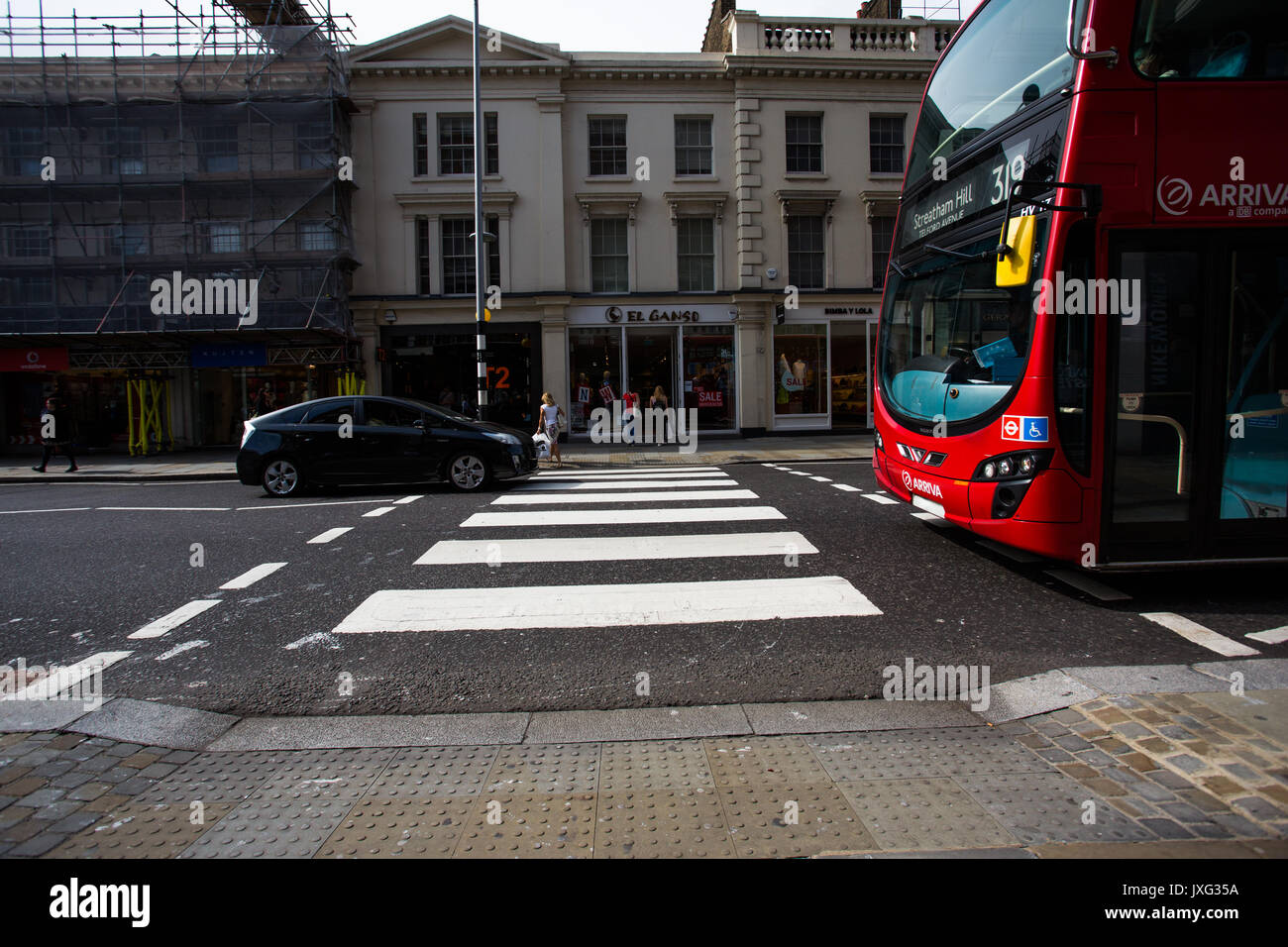 A Zebra Crossing with black Toyota Prius and red London Bus approaching ...