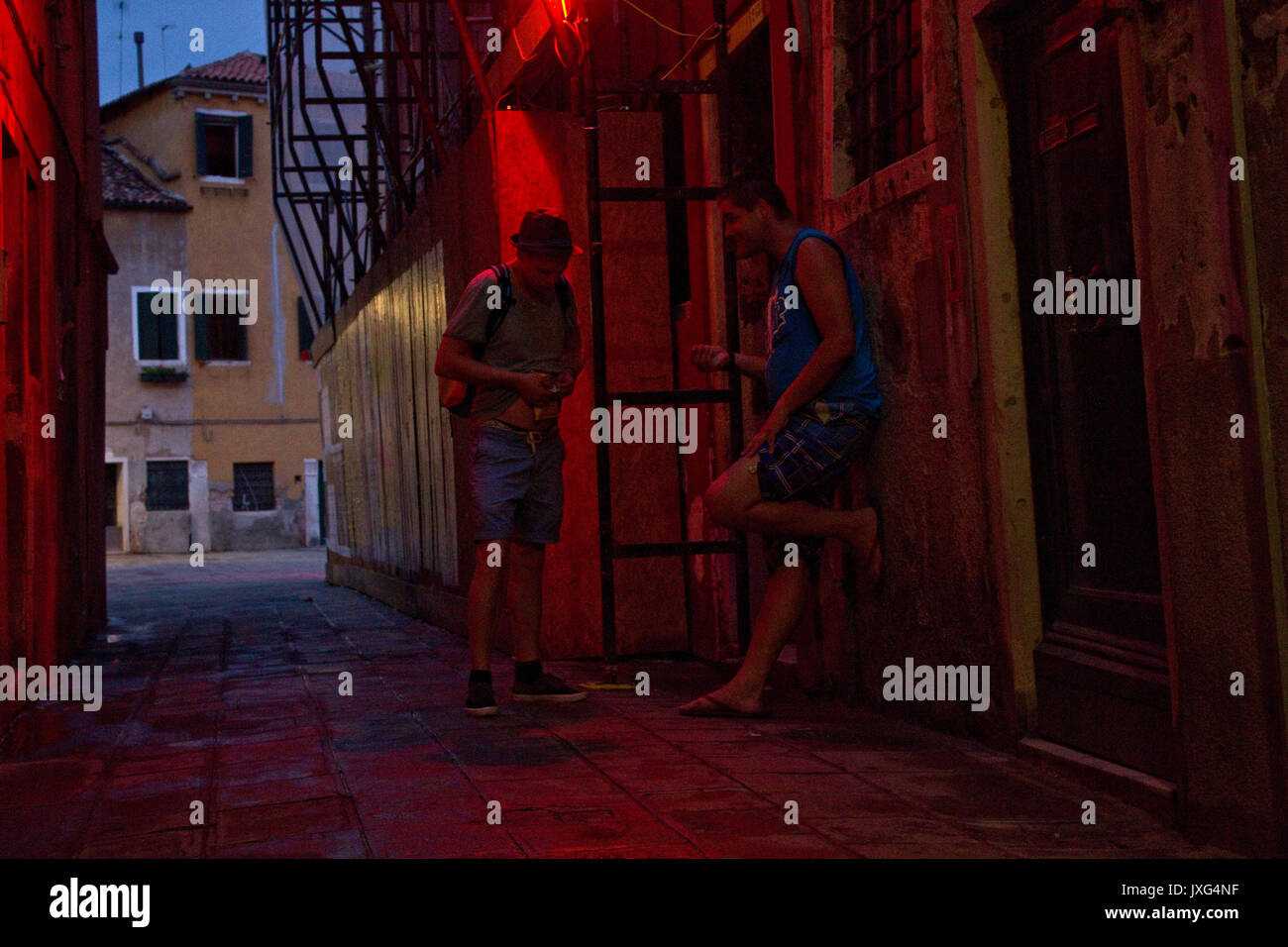 Two men talking in the street of red lights in Venice, Italy Stock ...