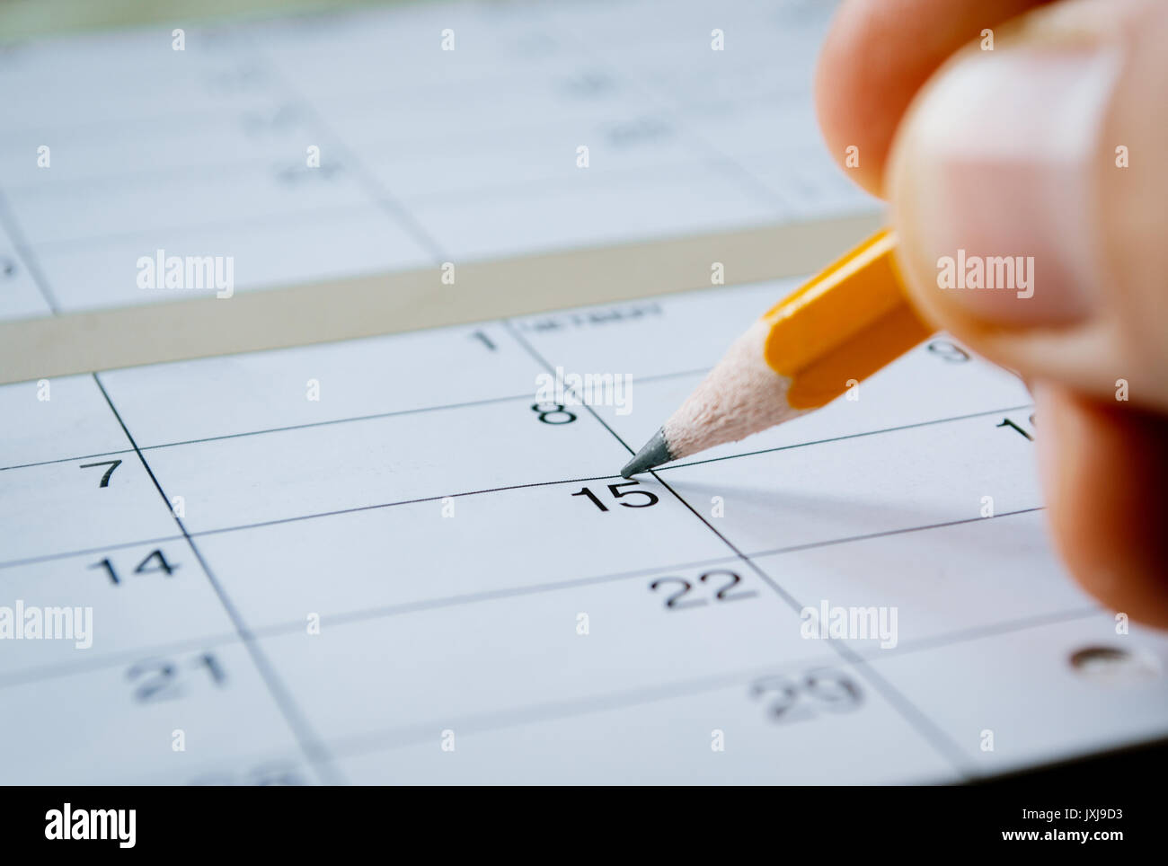 Person marking the date of the 15th with a pencil on a blank calendar ...