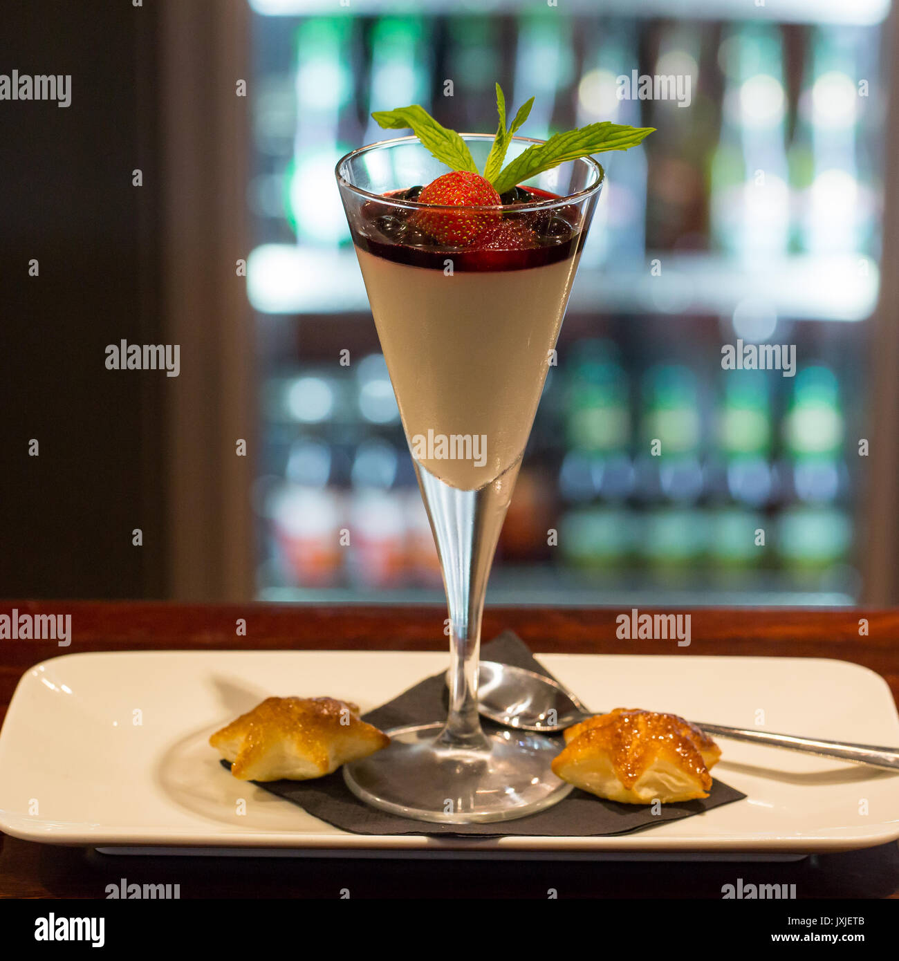 Elegant dessert in tall glass with bar fridge in background square crop ...