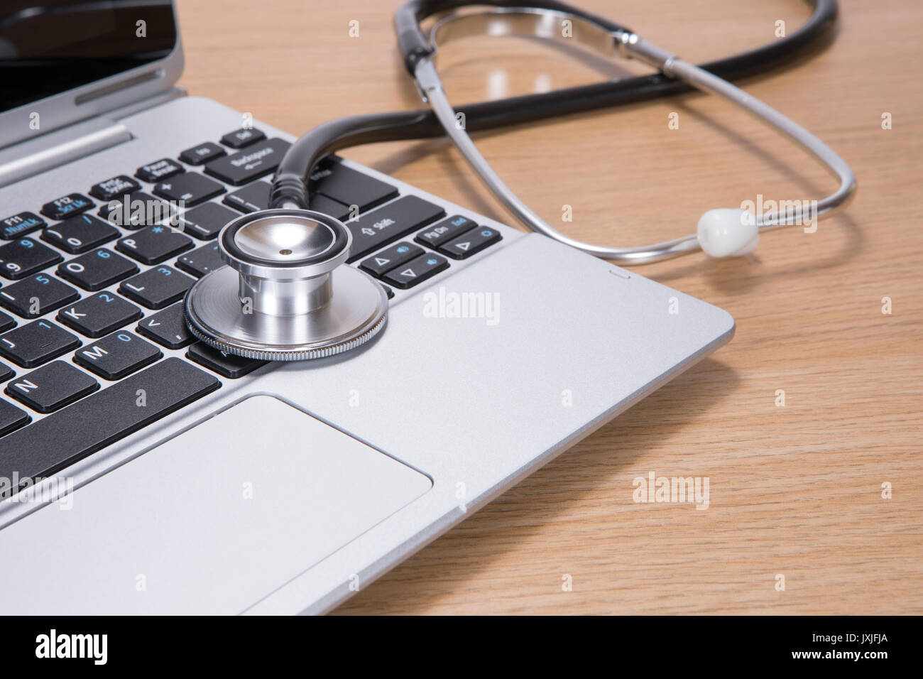 Angled view of silver and black medical stethoscope lying on laptop ...