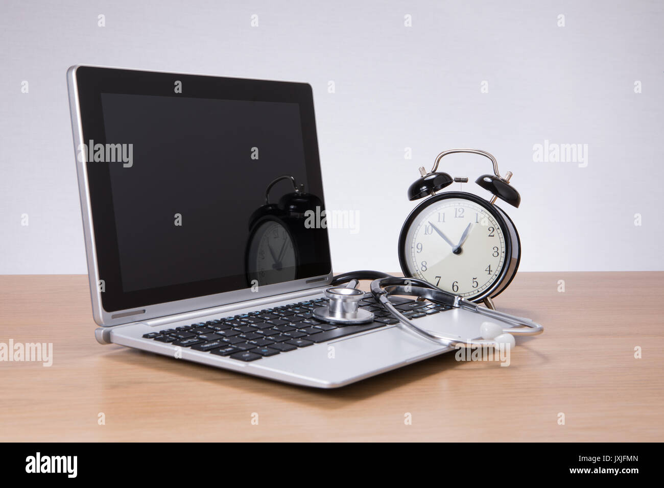 Side view of black and white alarm clock next to medical stethoscope ...