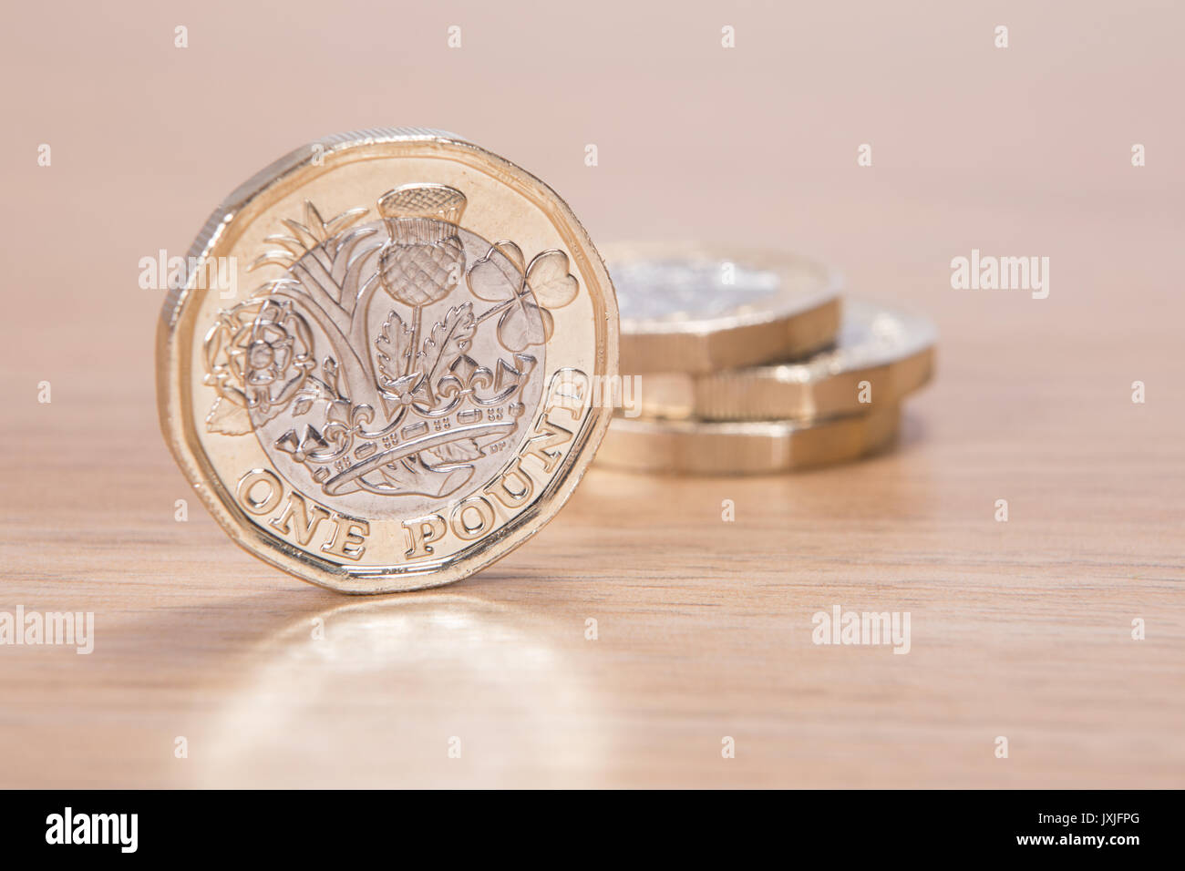 New British pound sterling coins on wood with one standing up on edge ...