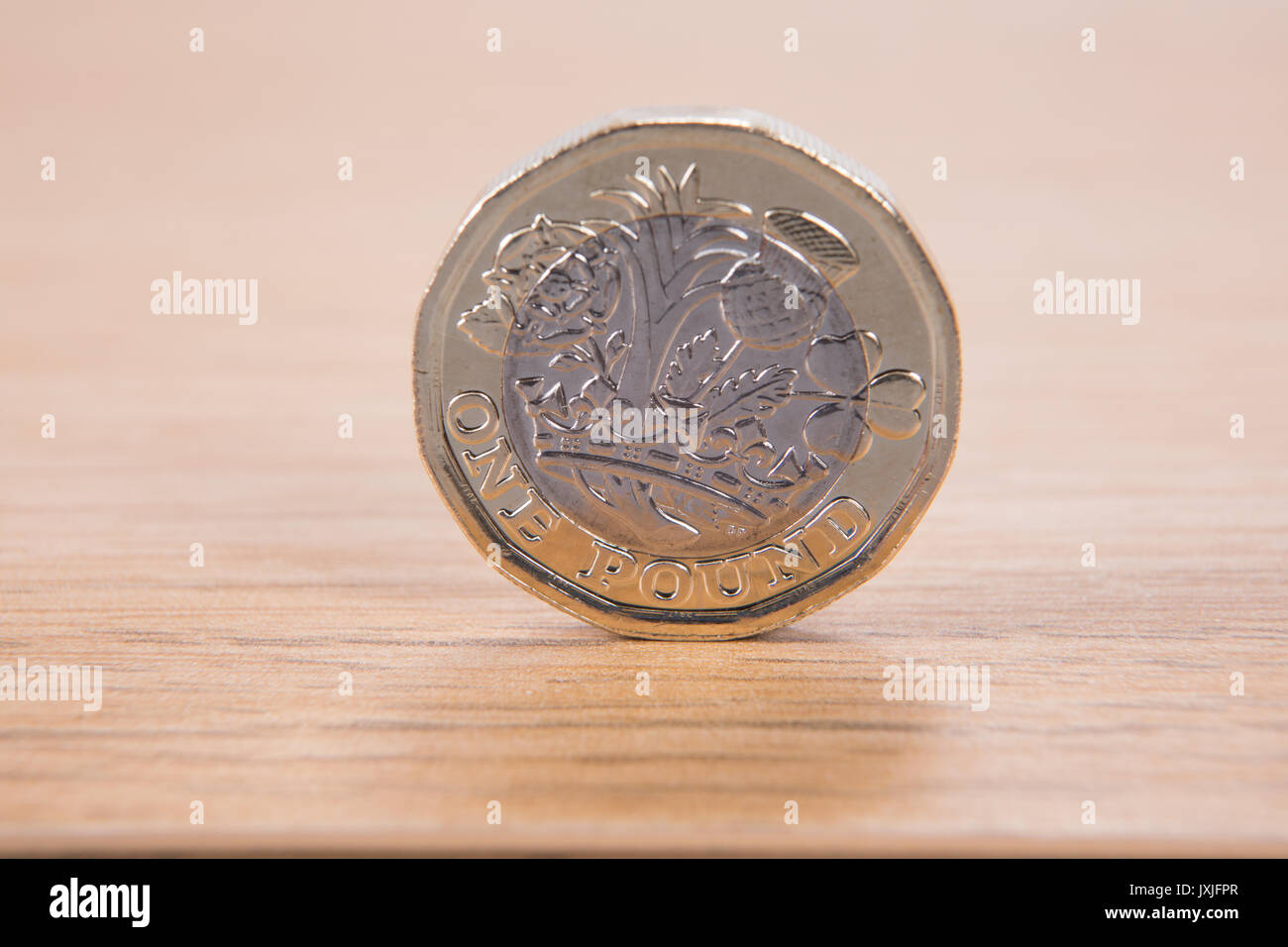 Single new UK pound sterling coin balancing upright on edge to show the ...