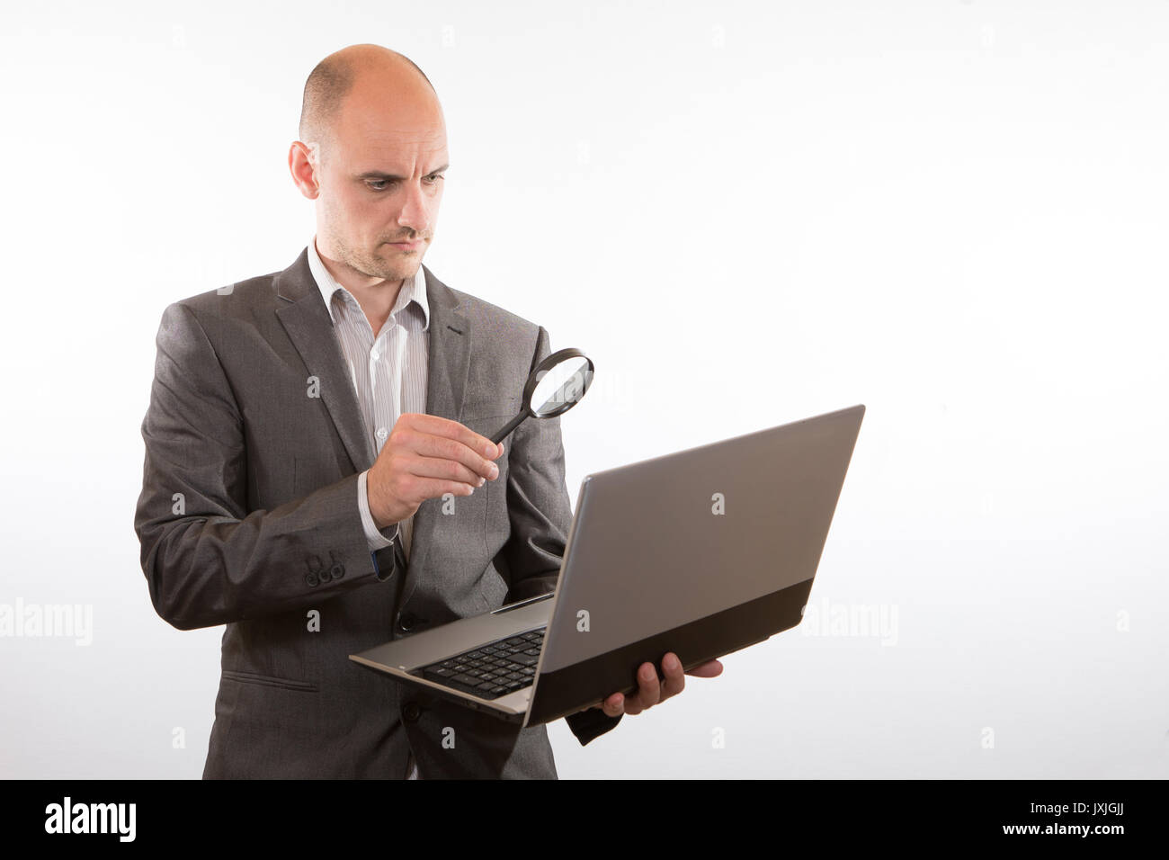 Businessman reading his laptop screen using a handheld magnifying glass ...