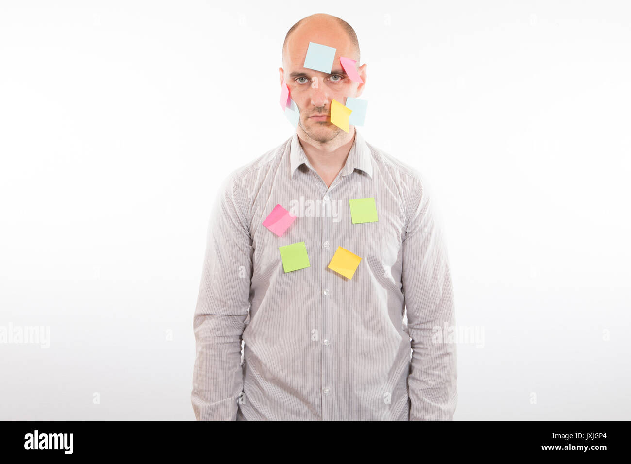 Serious man standing against white background covered with sticky notes ...