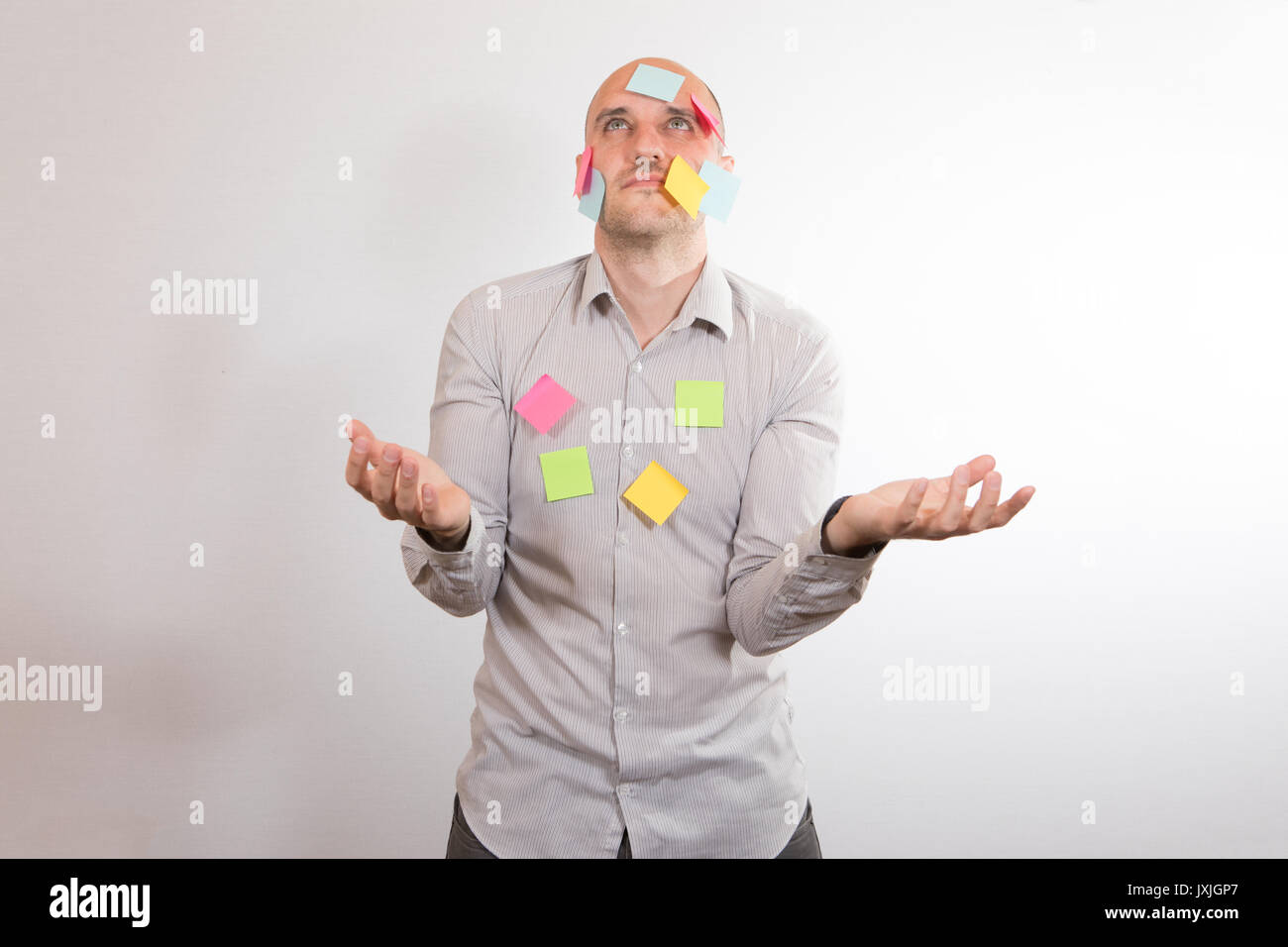 Helpless man covered with sticky notes standing against plain ...