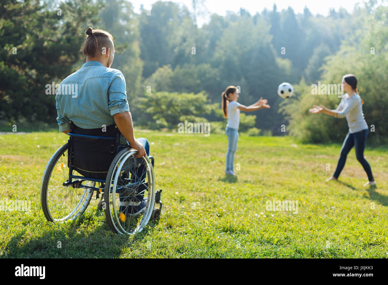 Mobility-impaired man watching his family play with ball Stock Photo ...