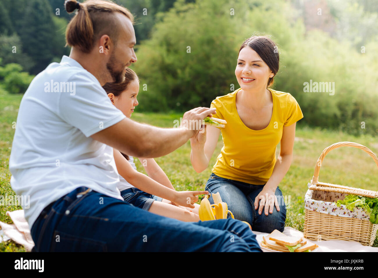 Pleasant young family sharing food on picnic Stock Photo - Alamy