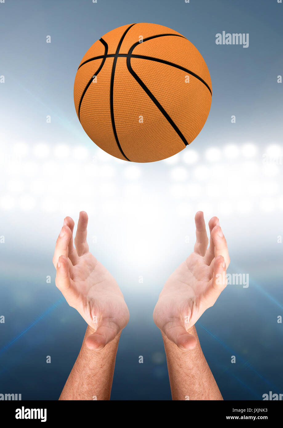 A pair of male hands reaching upwards to catch a basketball on a ...