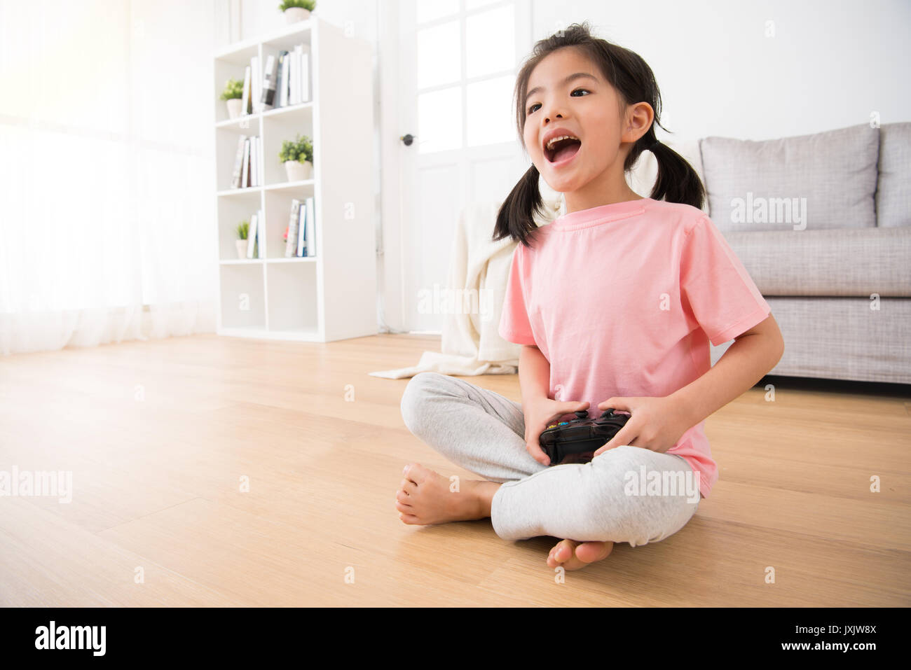 excited girl kid playing video game at home having fun after school day ...