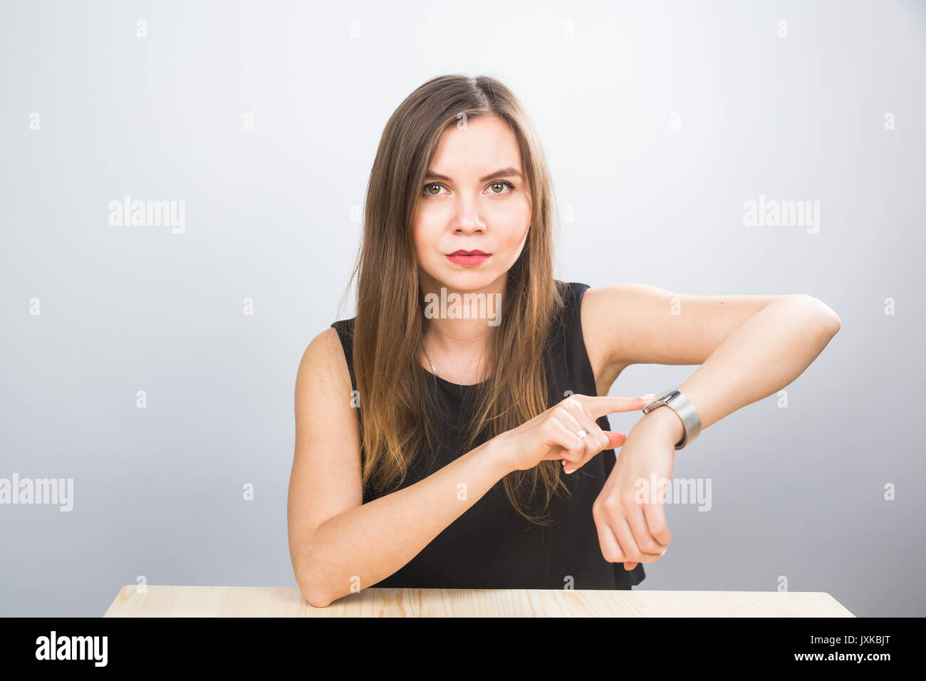Portrait of a young woman pointing finger on wrist watch Stock Photo ...