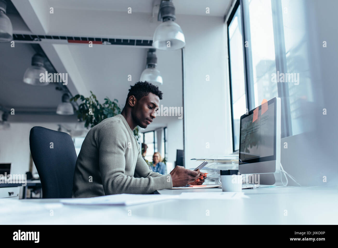 Male executive sitting in work place and using mobile phone. Young ...