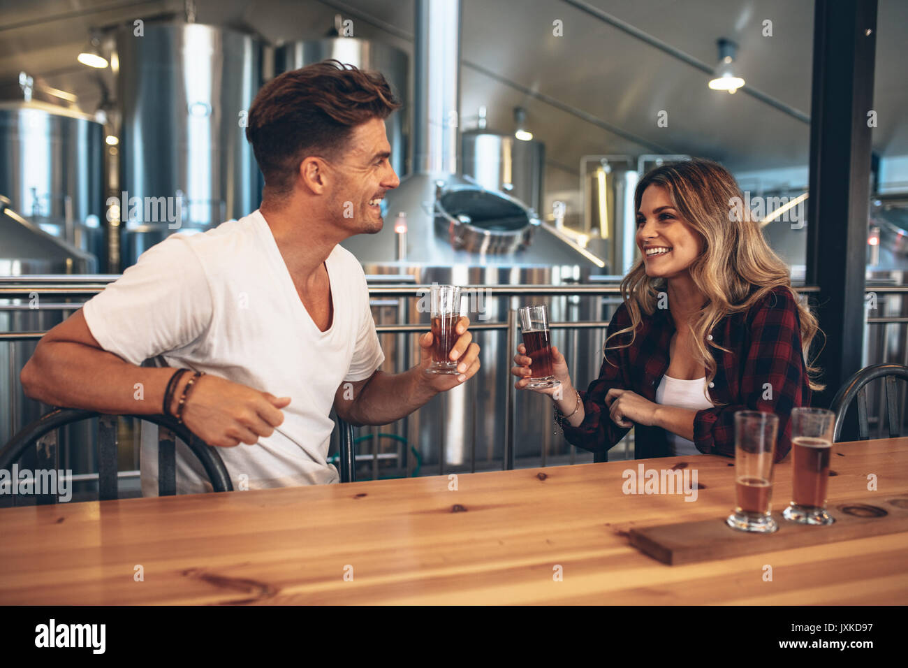Couple at brewery toasting beers. Young man and woman tasting different ...
