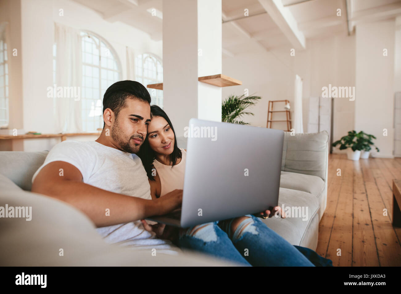Loving young couple sitting on sofa and using laptop computer. Young ...