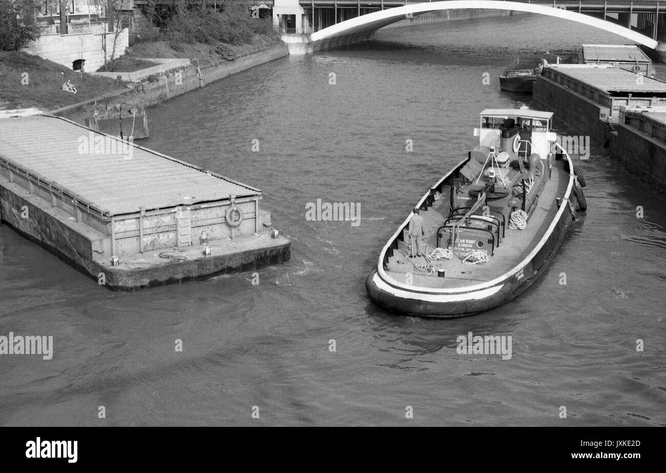 A tug boat prepares to tow a barge of refuse on the River Thames in ...