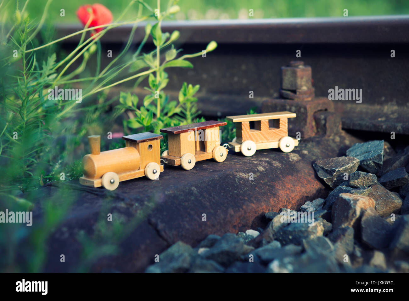 small wooden toy train on real railway tracks Stock Photo - Alamy