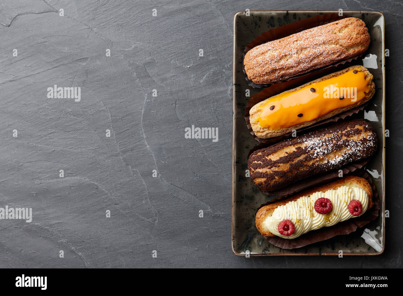 Rectangulare plate with different french eclairs on stone background ...
