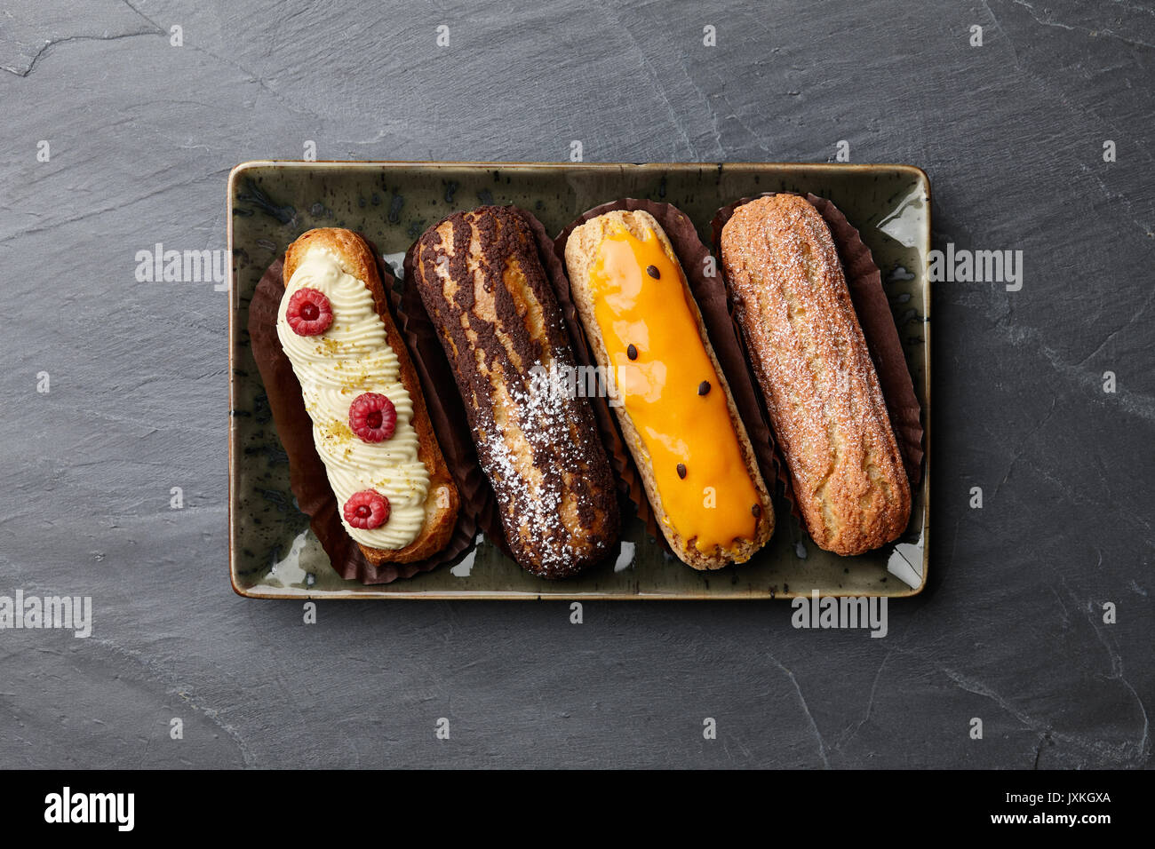 Rectangulare plate with different french eclairs on stone background ...