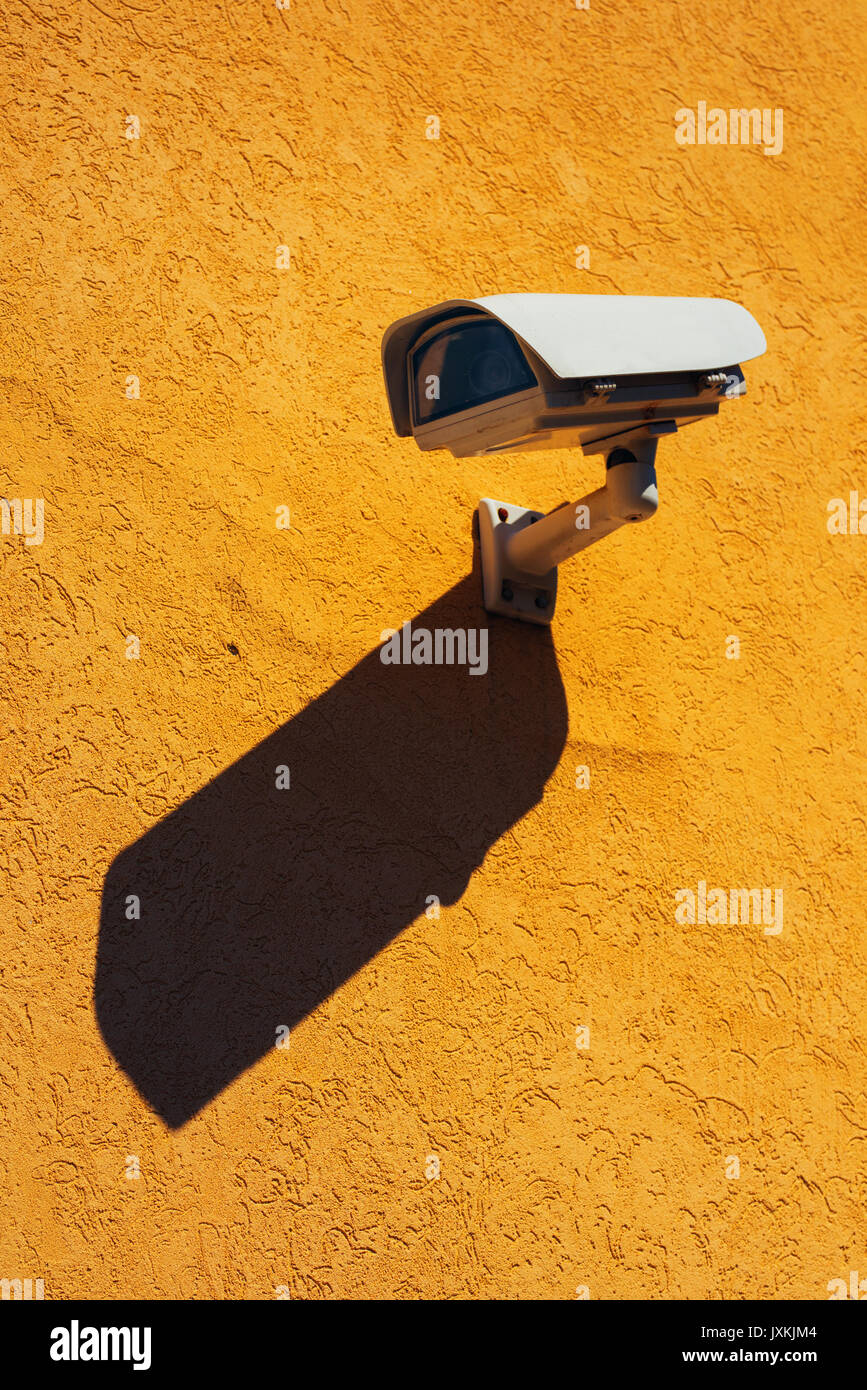 Security camera on yellow wall, modern surveillance technology on ...