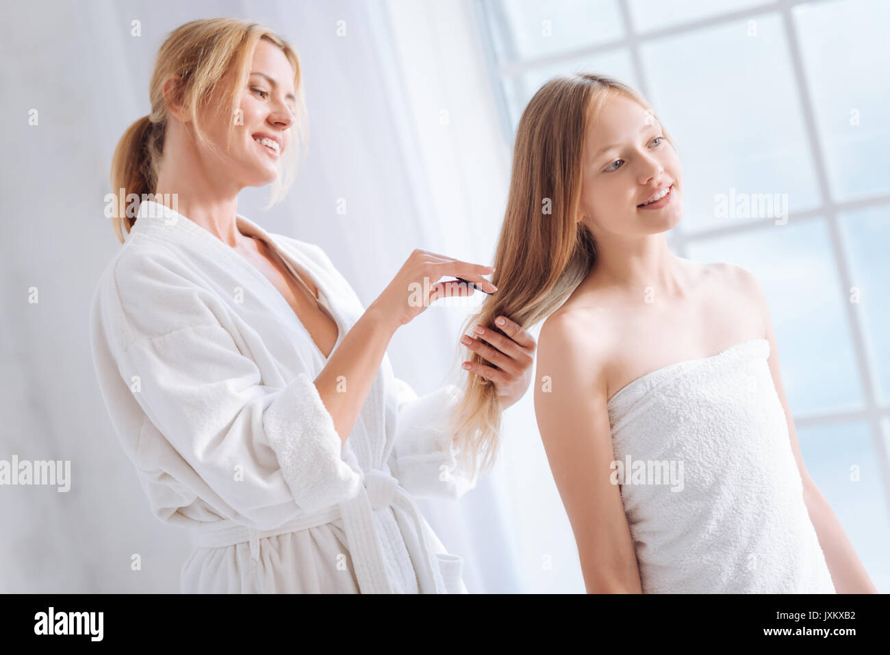 Cheerful woman combing clean hair Stock Photo - Alamy