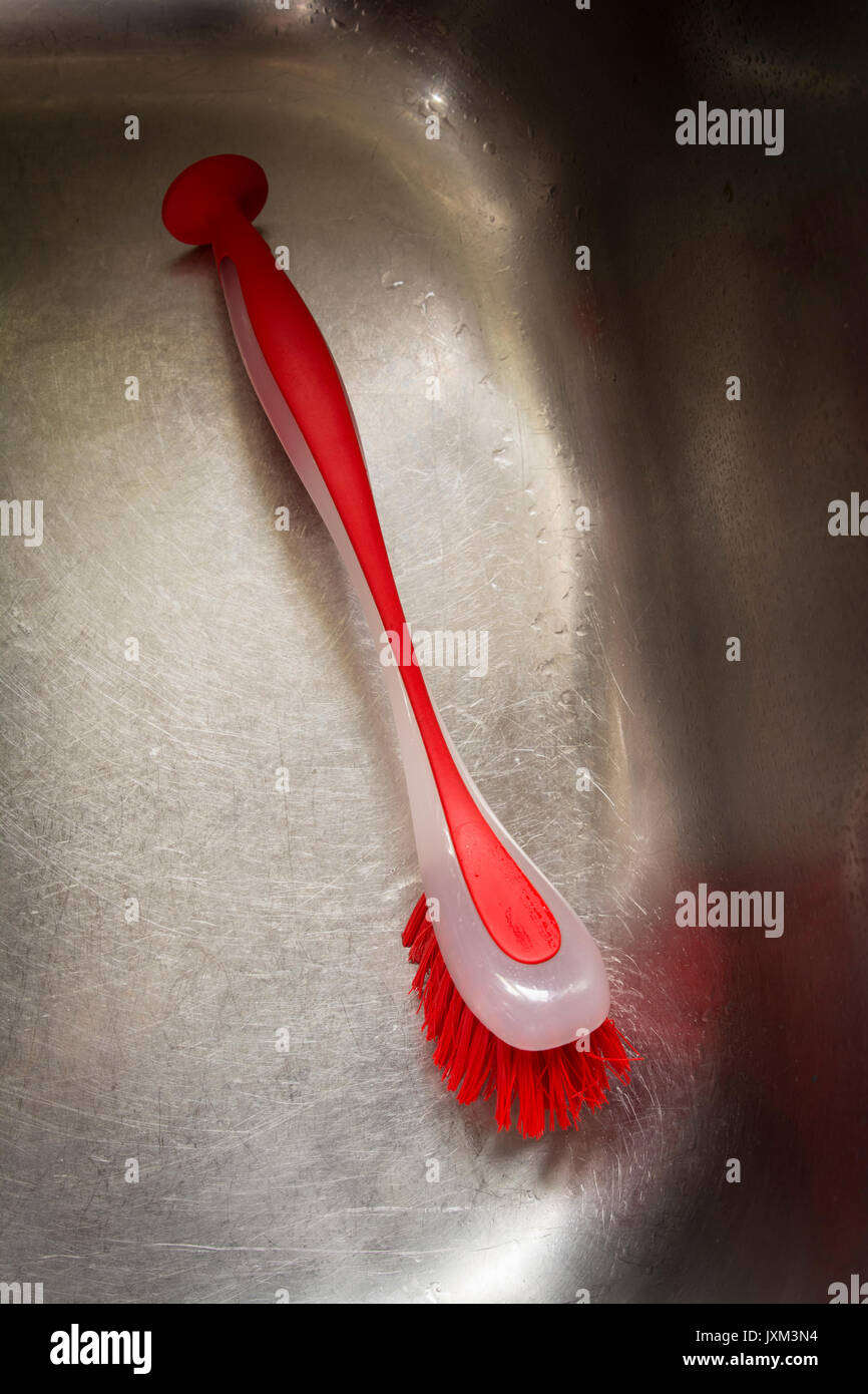 A red washing up scrubbing brush in a stainless steel shiny sink Stock ...