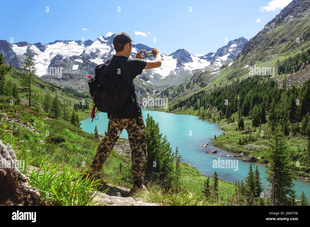 Tourist takes photos with smart phone on peak of hilly landscape. The ...
