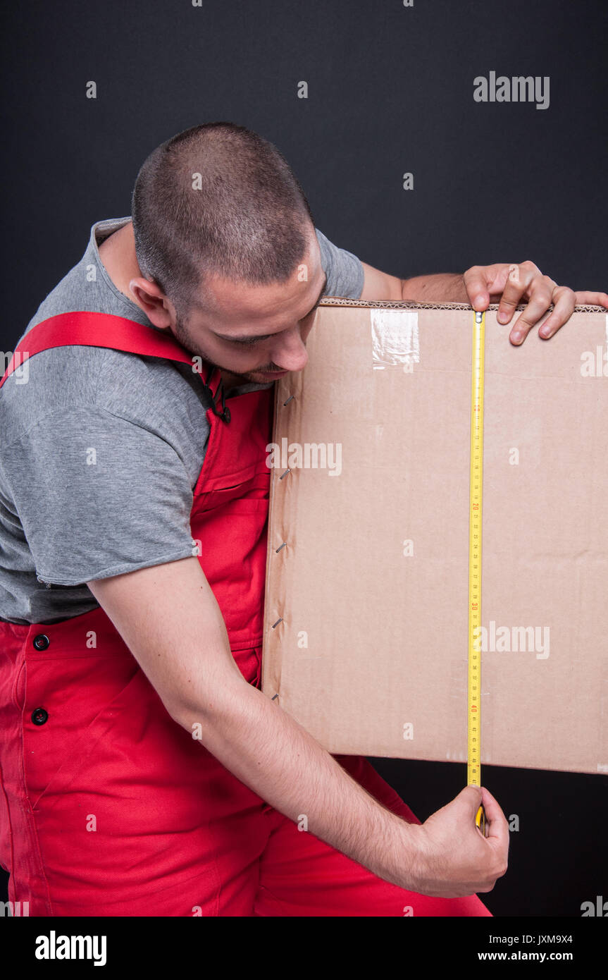 Mover guy holding box measuring with tape on black background Stock ...