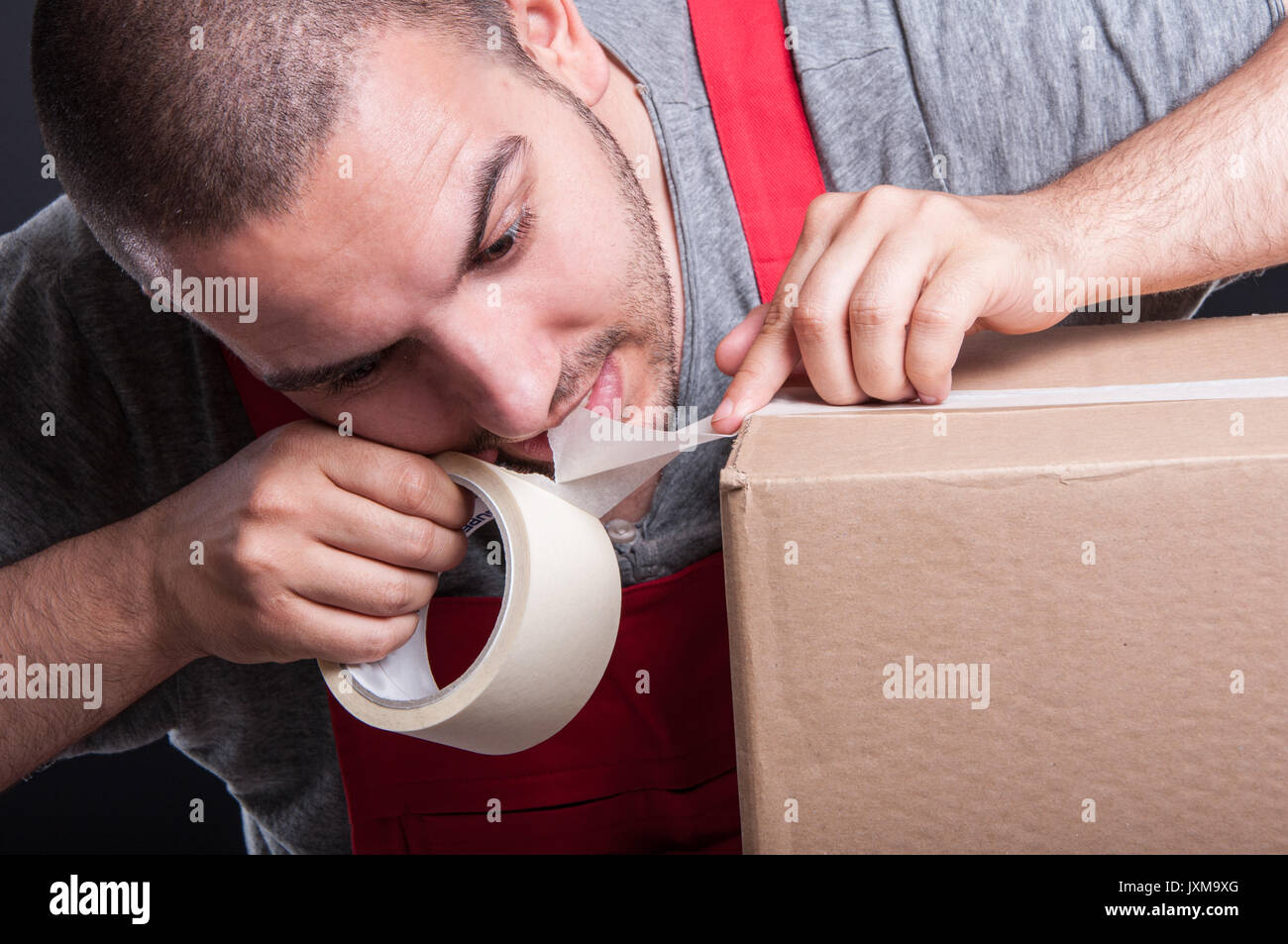 Close-up of mover guy ripping duct tape with teeth while packing ...