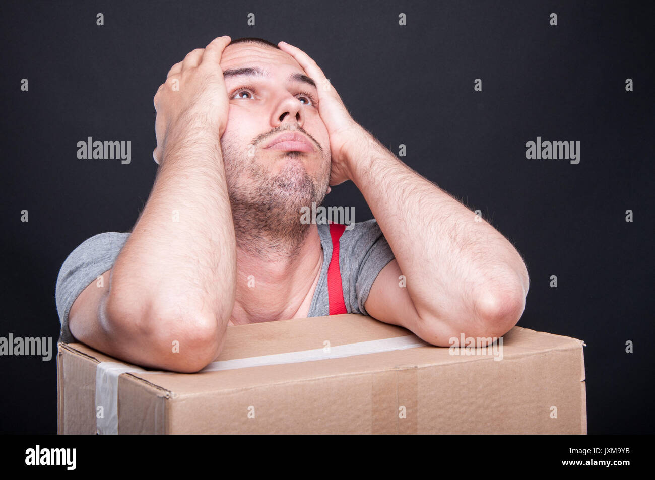 Mover guy making problem gesture on cardboard box with hands holding ...