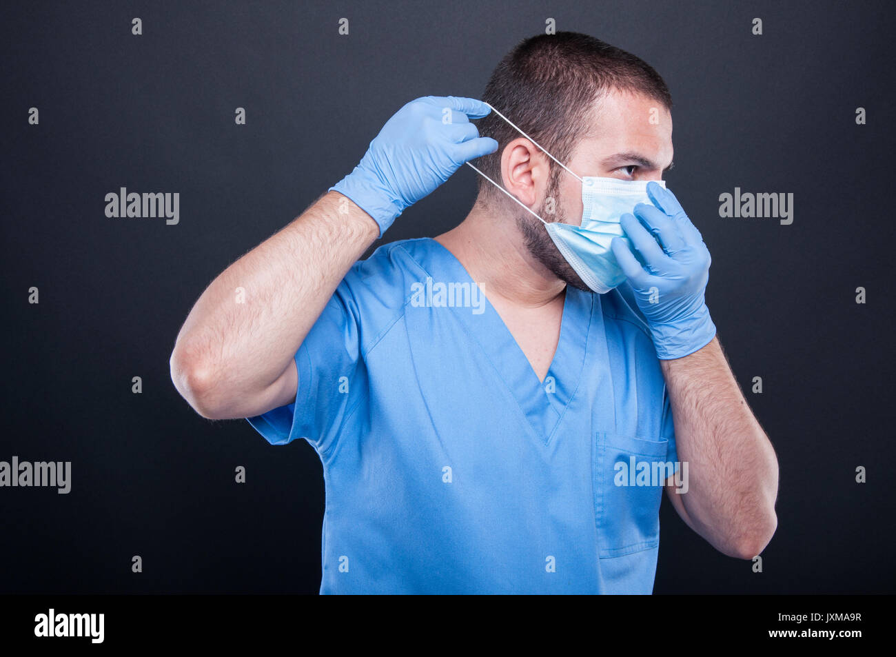 Side view doctor with scrubs and gloves putting on his sterile mask on ...