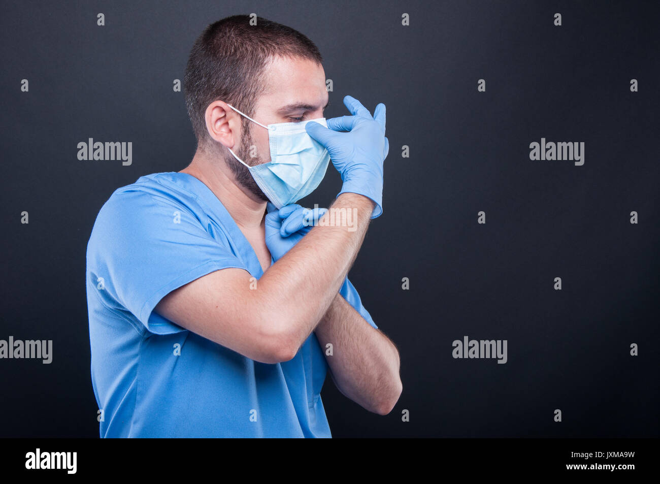 Side view doctor with scrubs and gloves fixing on his sterile mask ...